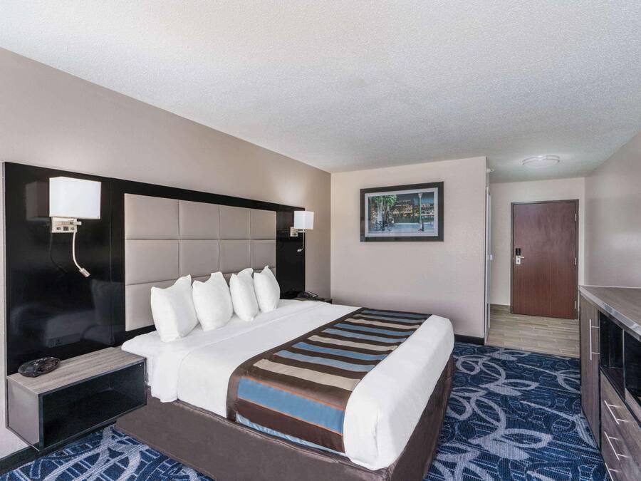 Quarto de hotel com cama, televisão de tela plana, escrivaninha e porta.