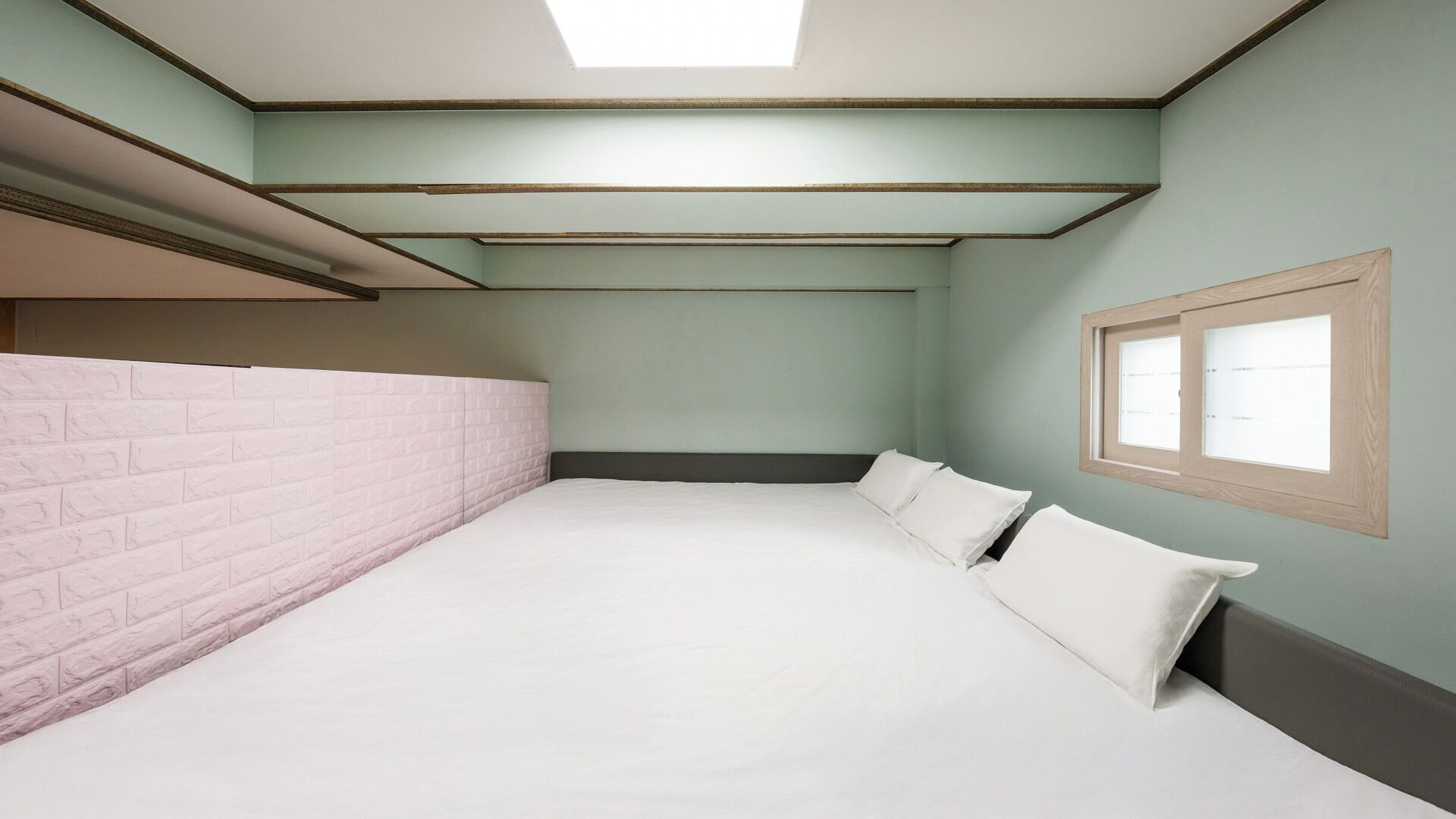 Quarto com uma cama, janela e parede de tijolos.