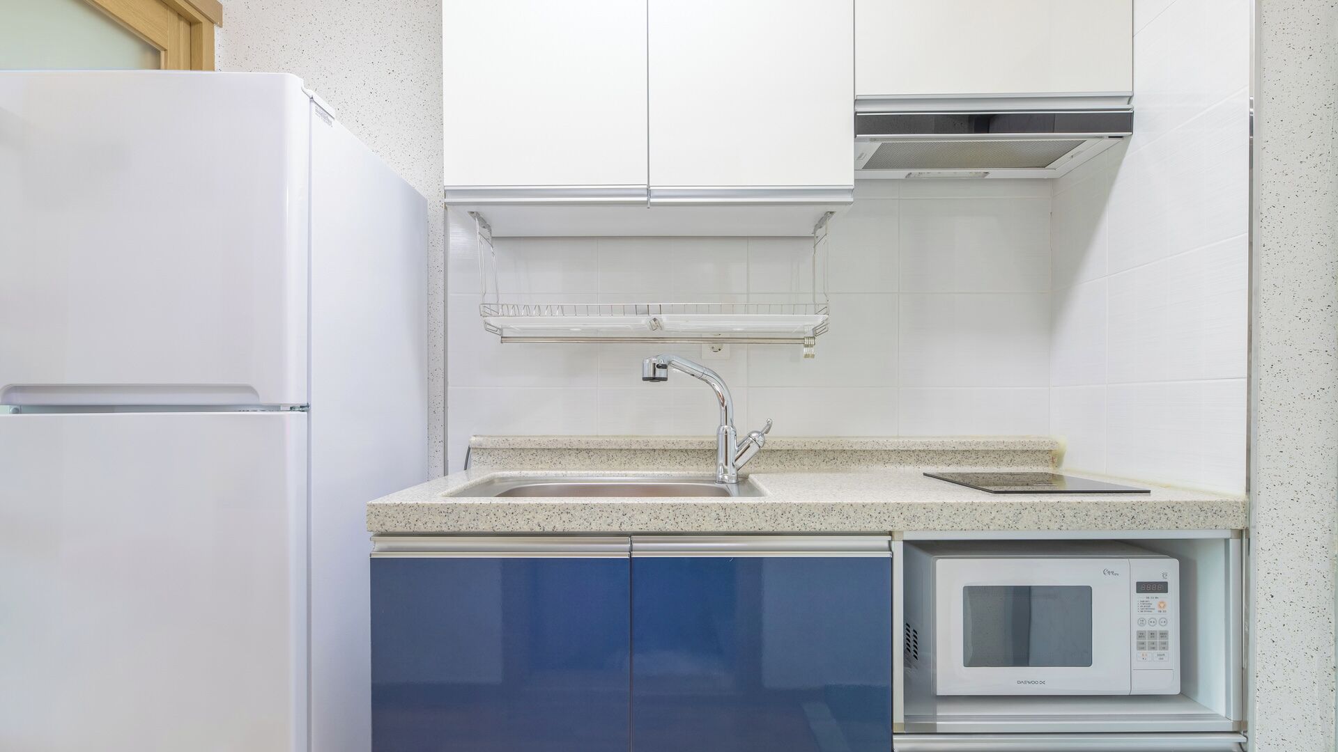 A kitchen with a white refrigerator, a built-in microwave, and a stainless steel sink.