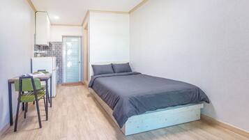 Quarto com cama, escrivaninha e cadeira.