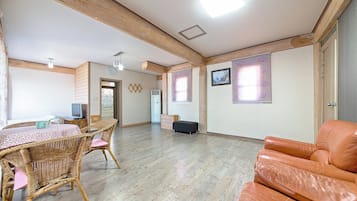 Quarto espaçoso com área de jantar, sofá e televisão.