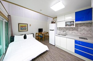 Quarto compacto com cama, uma pequena mesa de jantar, cozinha compacta e janela com vista.