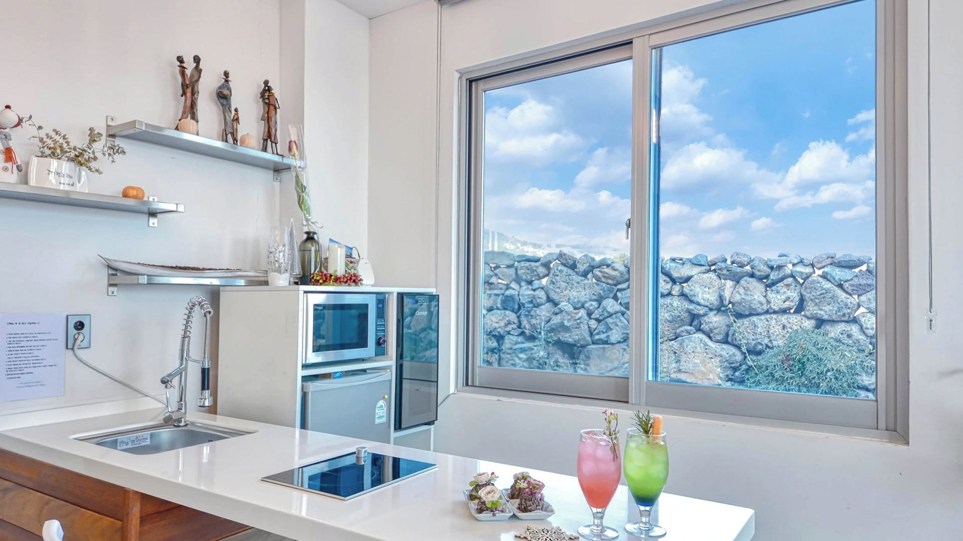 Cozinha moderna com uma grande janela, forno embutido e bancada com um tablet e objetos decorativos.
