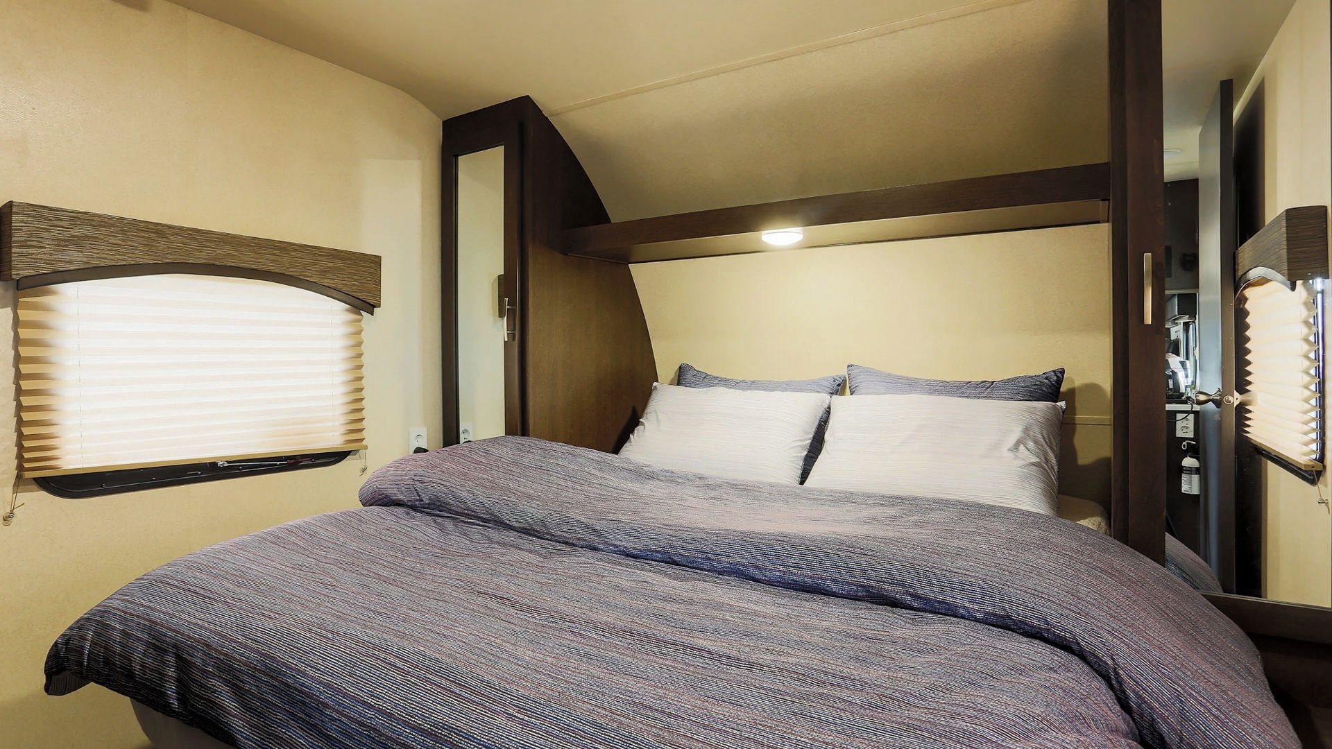 Quarto com cama, janela com persianas e espelho.