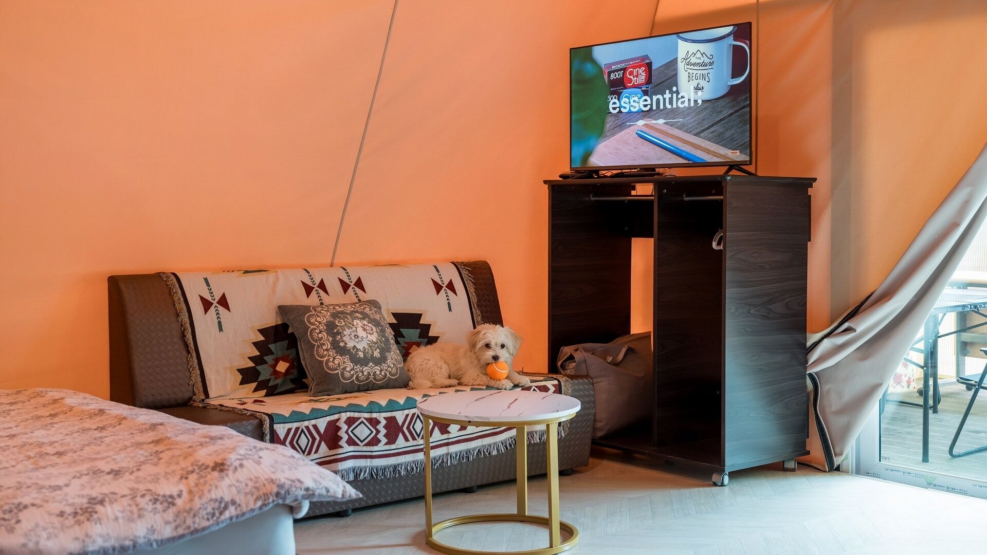Uma sala de estar aconchegante com um sofá, uma mesinha redonda, uma televisão e um guarda-roupa.