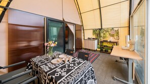 Alojamento em tenda com área de refeições, cozinha compacta e vista para o verde.