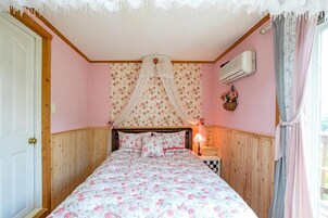 Quarto com colcha floral, cama de dossel, painéis de madeira, mesa de cabeceira com abajur e um aparelho de ar condicionado.