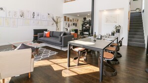 Uma sala de estar moderna com área de jantar, apresentando um sofá, uma mesa de centro de vidro e uma mesa de jantar com cadeiras.