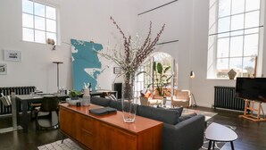 Uma sala de estar moderna com uma ilha de madeira, sofá cinzento e uma grande janela.