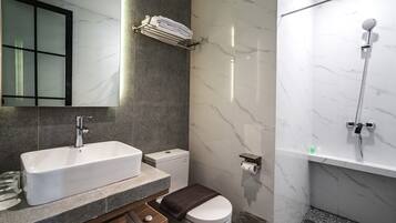 Uma casa de banho moderna com uma sanita, chuveiro, toalheiro e um lavatório retangular.