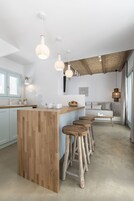 Cozinha moderna com ilha de madeira, banquetas, luminárias pendentes e teto rústico.