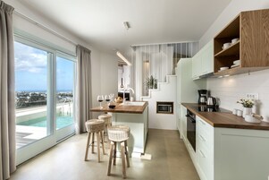 Uma cozinha moderna com uma ilha grande, banquetas e vista para o oceano.