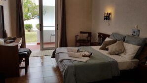 Quarto de hotel com cama, escrivaninha, cadeira e vista para o exterior.