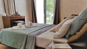 Uma cama bem arrumada com um cobertor verde, um travesseiro e um livro em uma mesinha de cabeceira.