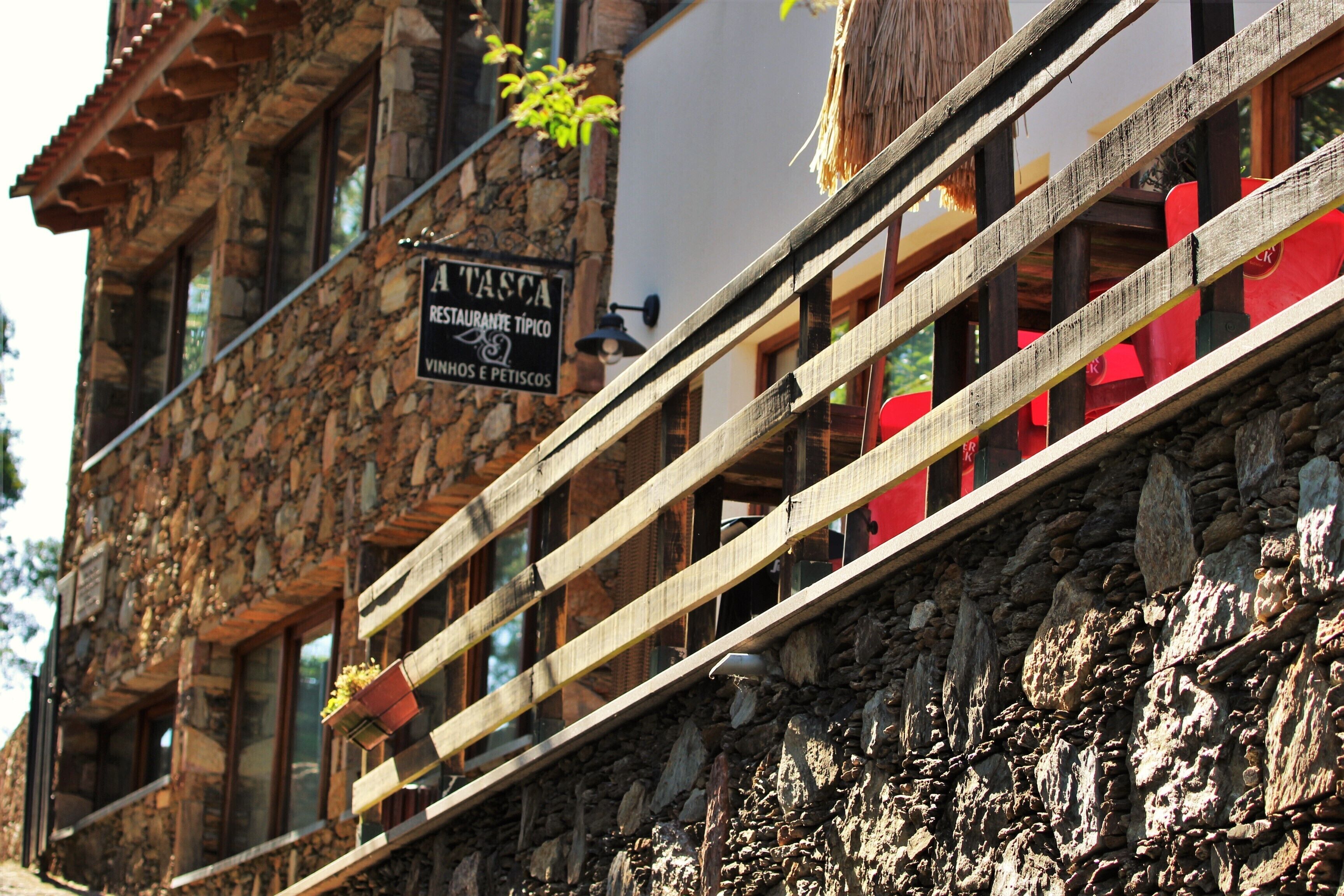 Um edifício de pedra com uma placa que diz 'A TASC A RESTAURANTE TÍPICO VINHOS E PETISOS'.