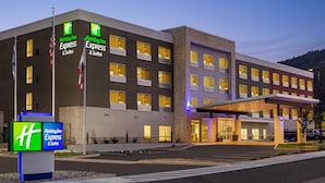 Edifício Holiday Inn Express & Suites com design moderno, várias varandas e entrada bem iluminada.