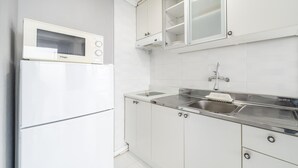 Uma cozinha com geladeira branca, micro-ondas, pia e armários.