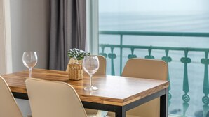Uma mesa de jantar com duas taças de vinho e uma pequena planta em cesta, com vista para o corrimão de uma varanda.