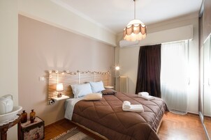 Uma cama bem arrumada com um edredom marrom, uma luminária de cabeceira e uma mesa de apoio com uma lâmpada.
