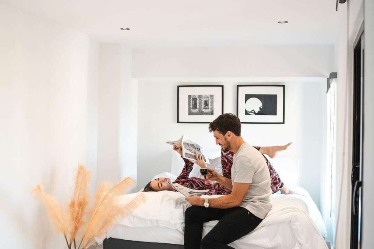 Quarto moderno com cama, mesa de cabeceira, banheira e duas fotos emolduradas na parede.