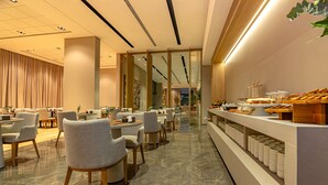 Restaurante moderno com chão de mármore, mesas redondas e cadeiras.