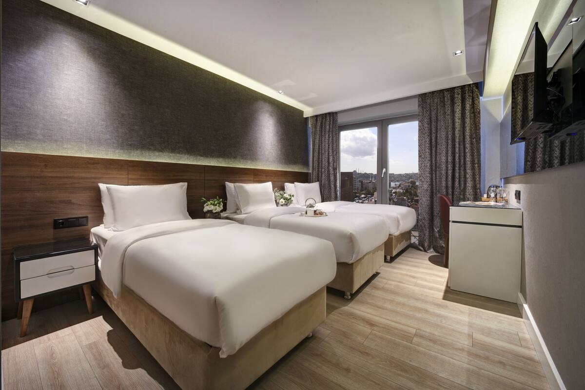 Quarto de hotel com duas camas, uma escrivaninha e vista para a cidade.
