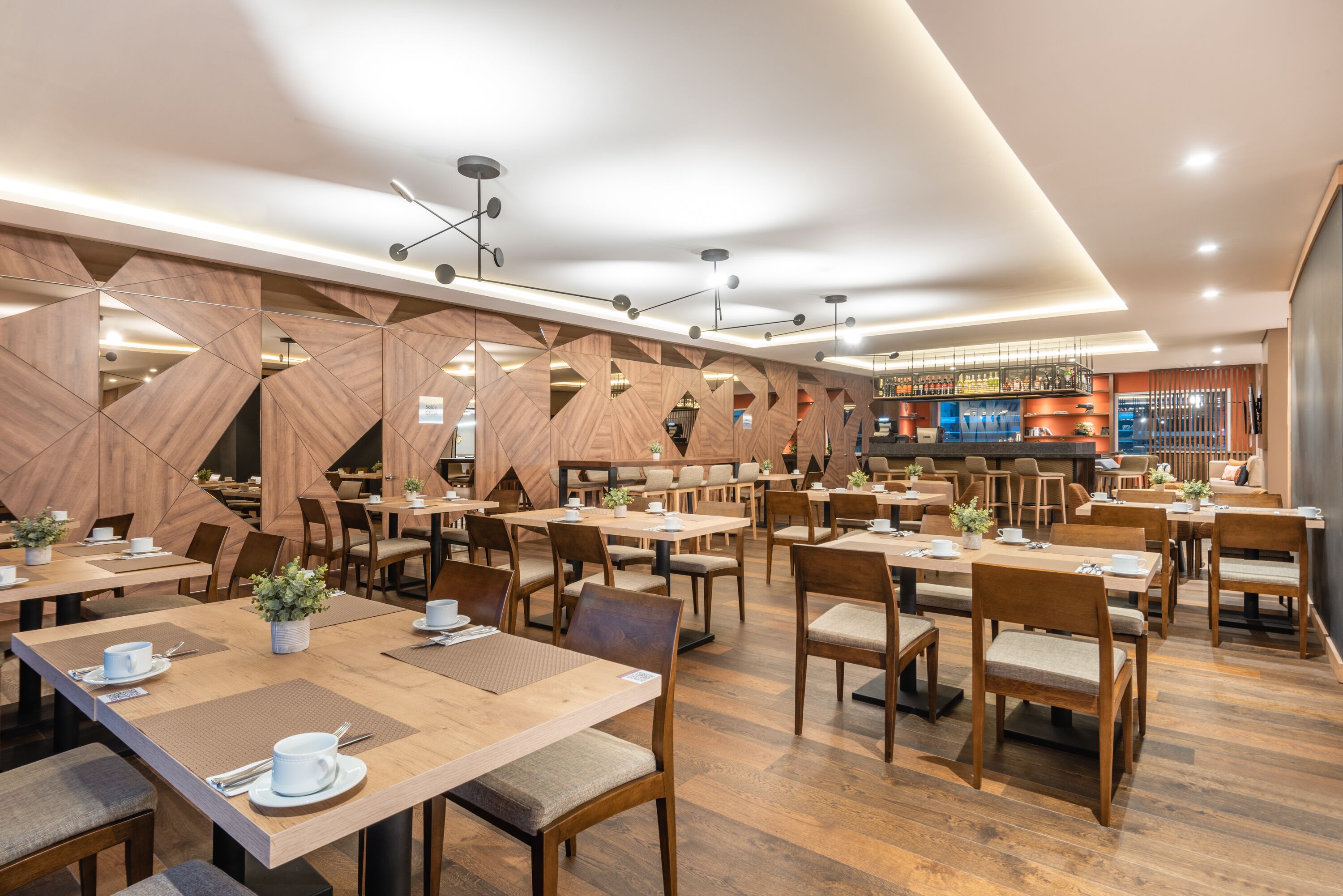 Um restaurante moderno com paredes revestidas de madeira, várias mesas e cadeiras.