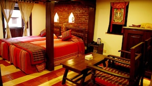 Quarto tradicional com duas camas, uma mesa de madeira e uma cadeira.