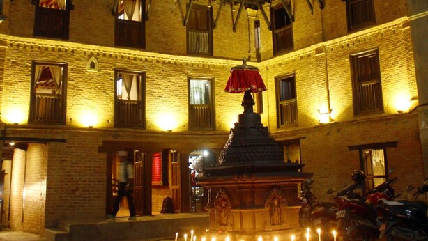Um pátio com uma fonte tradicional, rodeado por edifícios com vários andares, varandas e janelas.