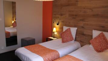 Quarto de hotel com duas camas, um espelho, uma mesa de cabeceira com abajur e uma parede de madeira.