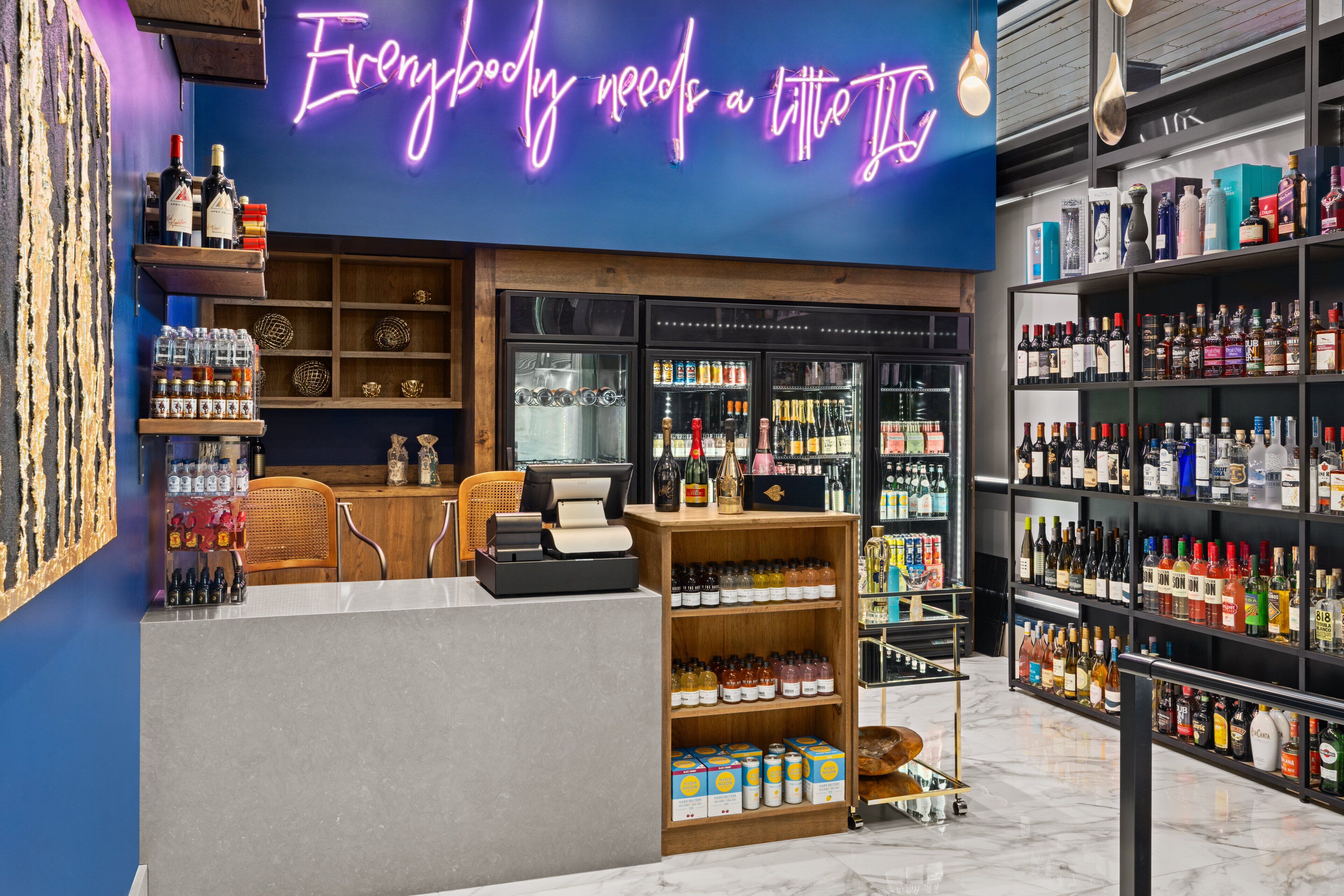 Uma loja de bebidas com prateleiras cheias de garrafas, um letreiro de neon e um caixa registradora.