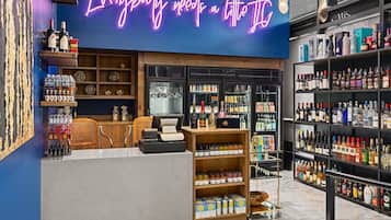 Uma loja de bebidas com prateleiras cheias de garrafas, um letreiro de neon e um caixa registradora.