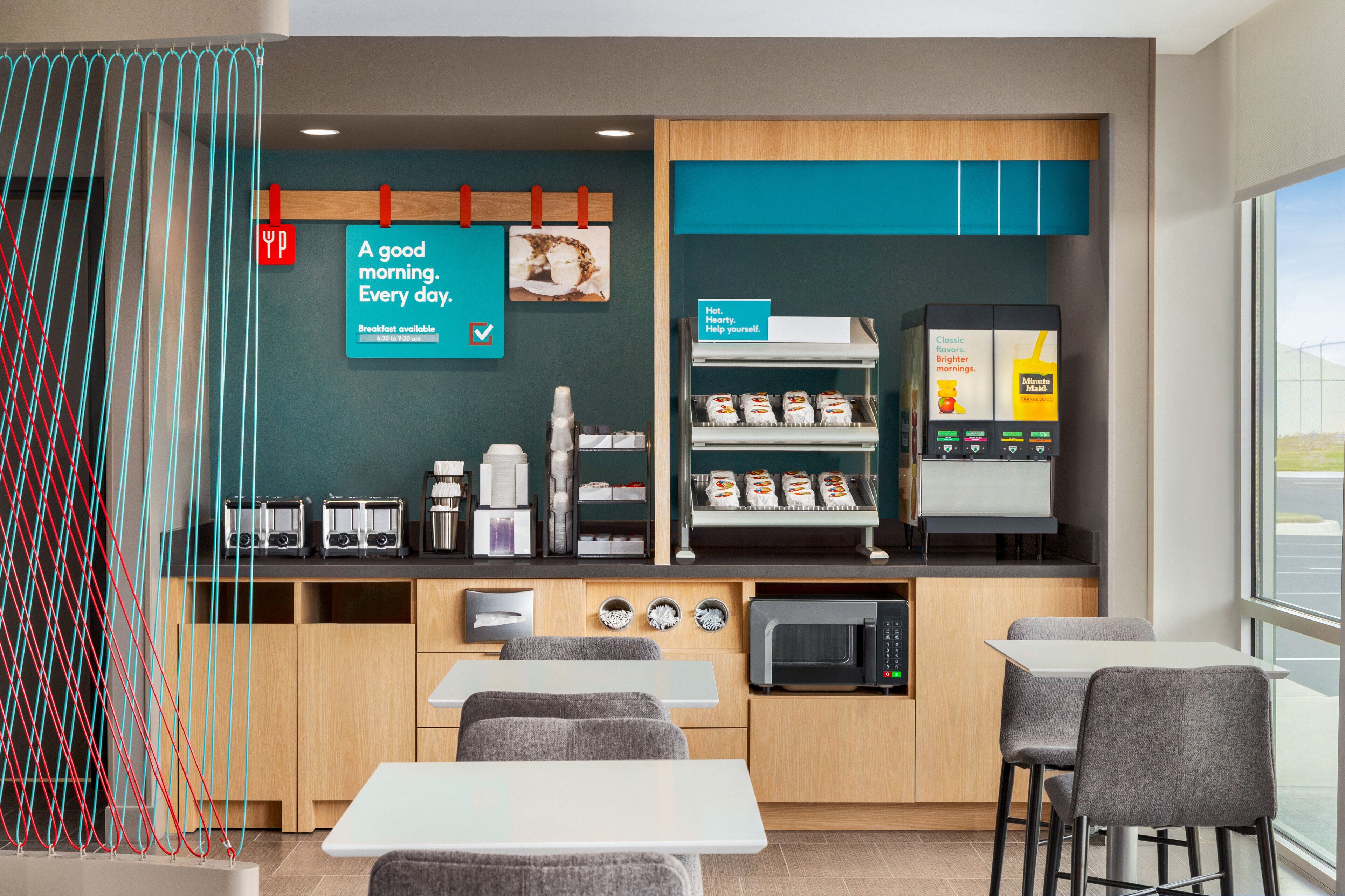 Uma área de café da manhã moderna com máquina de café, torradeira e placa indicando horário do café da manhã.