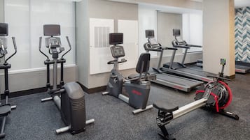 Uma academia com diversos equipamentos de exercícios, incluindo esteiras, bicicletas ergométricas e aparelhos de musculação.