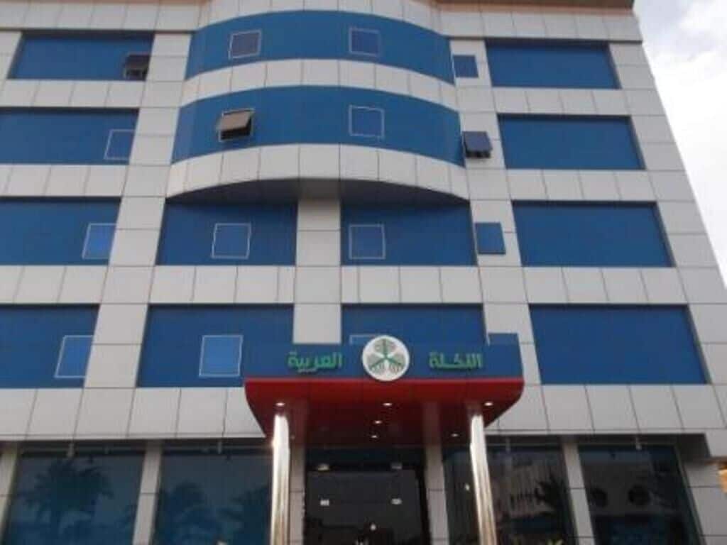 Um edifício de vários andares com fachada azul e branca, apresentando uma entrada destacada com toldo vermelho.