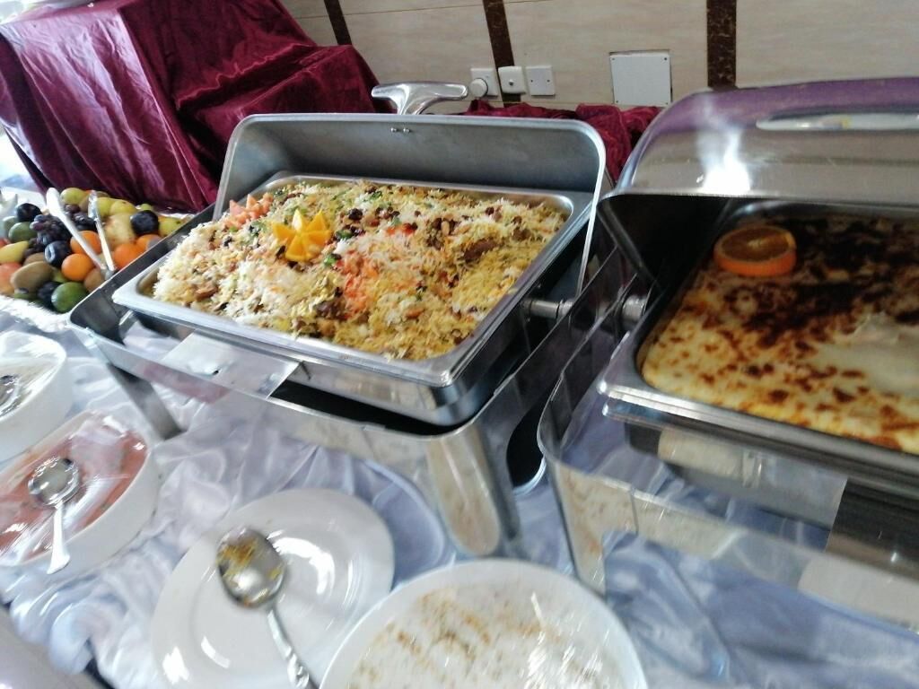 Uma mesa de buffet com diversos pratos, incluindo arroz e um item assado, e um prato de frutas.