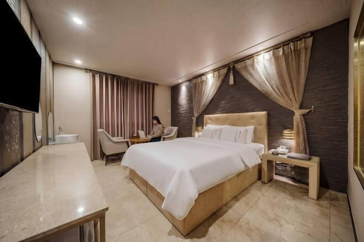 Quarto de hotel moderno com uma cama grande, uma escrivaninha e uma cadeira.