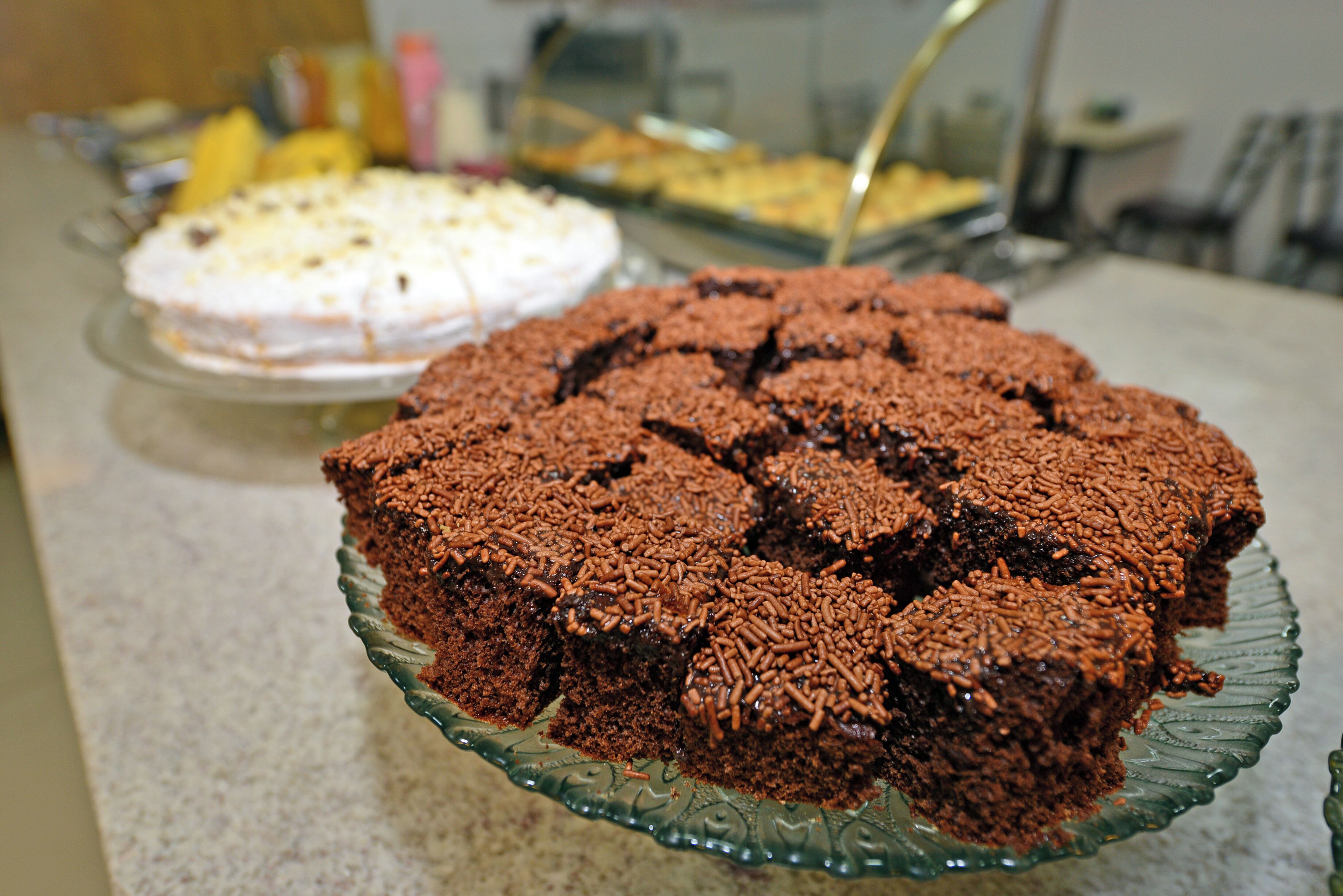 Um suporte de vidro para bolo com brownies e um bolo branco.