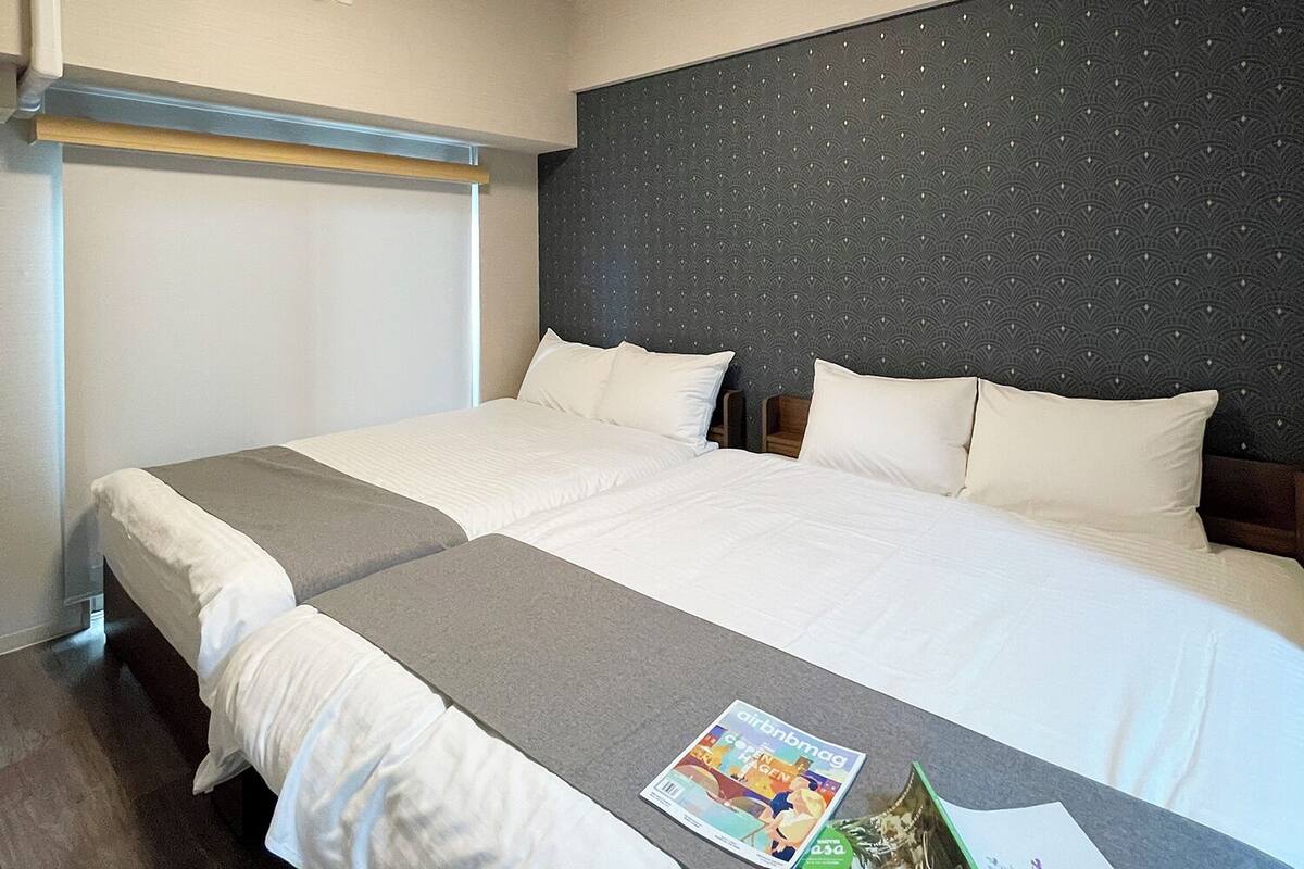 Quarto de hotel com uma cama grande, cabeceira com padrão texturizado, aparelho de ar condicionado e luminária no teto.
