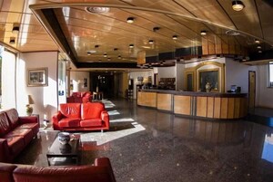 Um hall amplo com balcão de recepção, sofás de couro vermelho e piso polido.