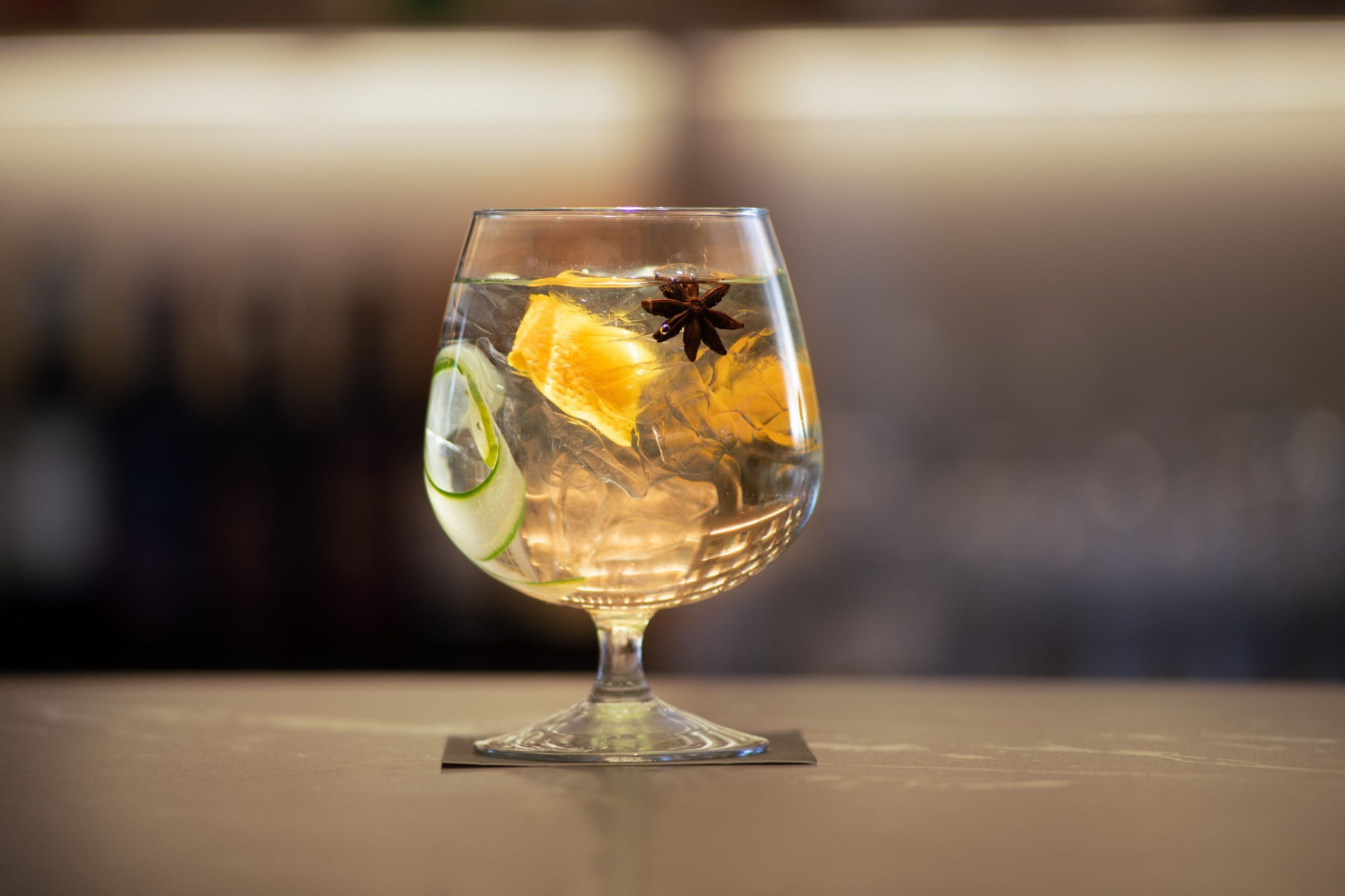 Um copo com cubos de gelo, uma fatia de laranja e uma estrela-de-aniz sobre uma mesa.