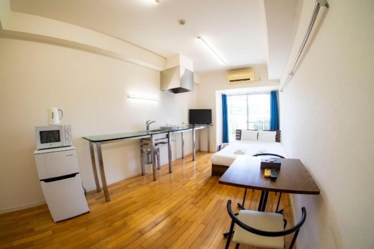Cozinha compacta com micro-ondas, pia e área de refeições com mesa e cadeiras.