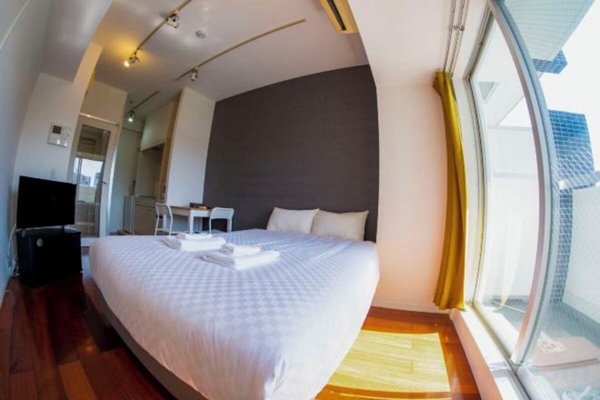 Quarto de hotel com uma cama grande, uma mesa e uma janela.