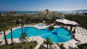 Um resort com uma piscina central ampla, várias piscinas menores e uma área de praia.