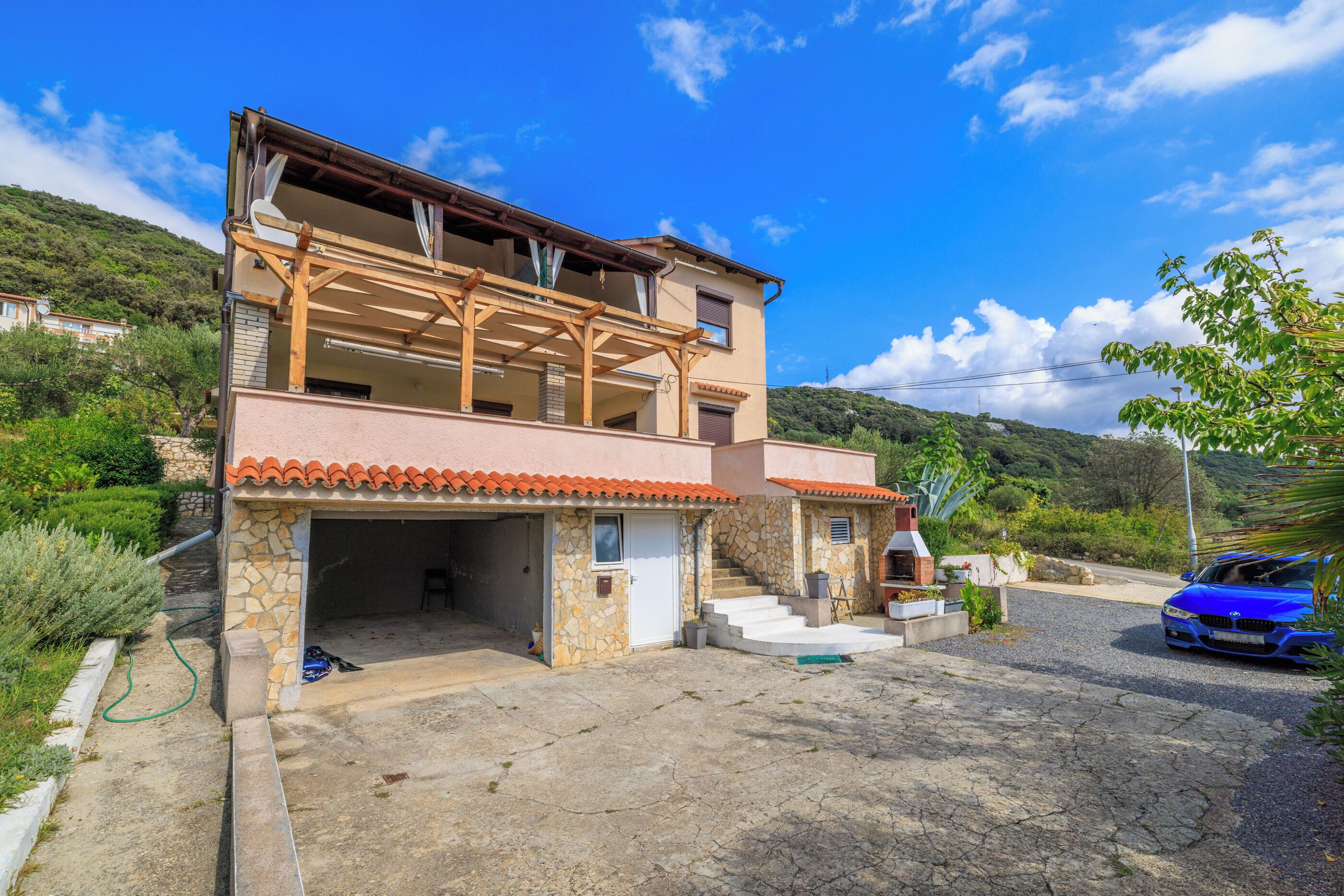 Uma casa de dois andares com fachada de pedra e telhado de telhas vermelhas, e uma garagem.