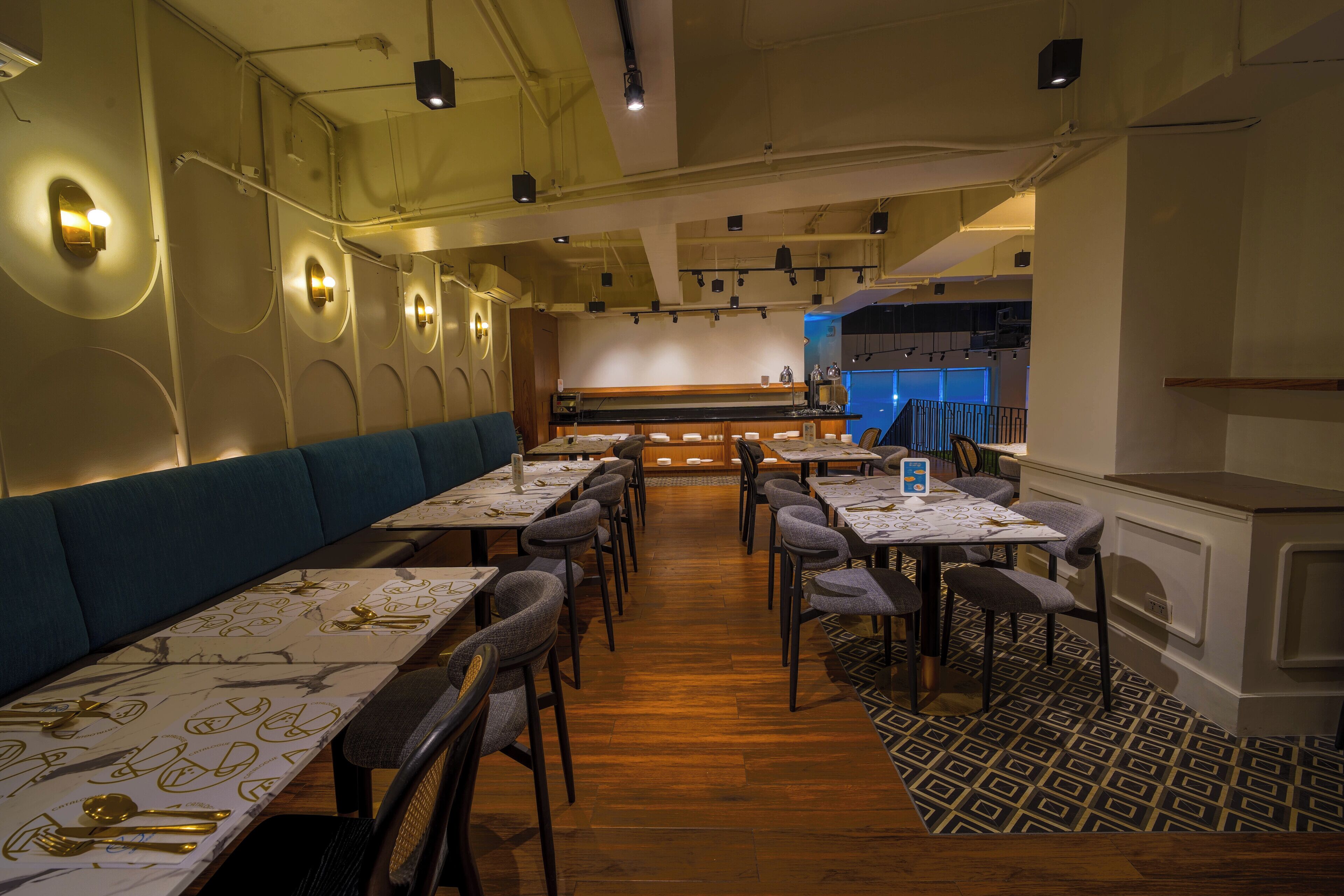 Um restaurante com cabines e mesas, um espaço de bar e uma cozinha ao fundo.