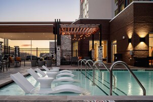 Área de piscina com pérgola, assentos externos e vista para a paisagem urbana.