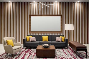 Uma sala de estar moderna com sofá, poltrona, mesa de centro e uma tela grande em branco.
