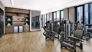 Uma academia moderna com equipamentos de ginástica, piso de madeira e vista através de uma porta de vidro.