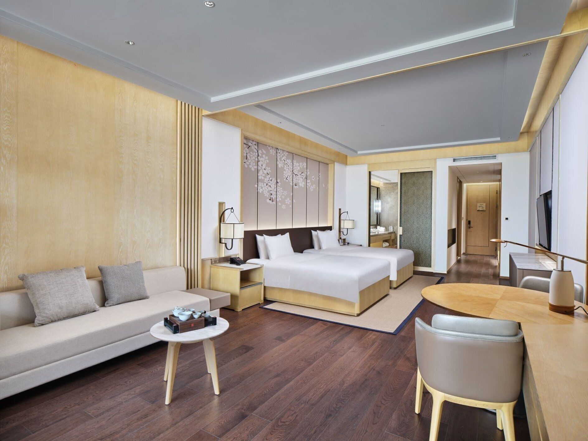 Quarto de hotel moderno com uma cama grande, um sofá, uma mesa de jantar e uma televisão.